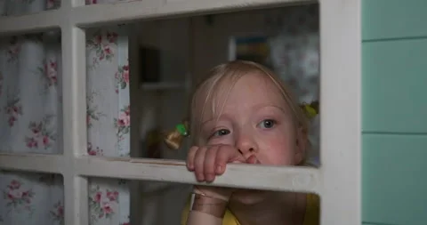 Little girl peeks out of window in child... | Stock Video | Pond5