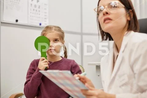 Photograph: Little Girl Reading Eye Chart at Vision Test #122914872