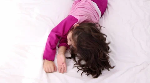 Little girl is rolling on a bed | Stock Video | Pond5
