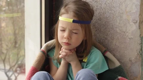 a little girl sits at the window and pra... | Stock Video | Pond5