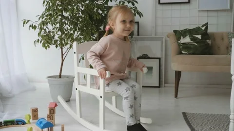 Little girl sitting in rocking chair | Stock Video | Pond5