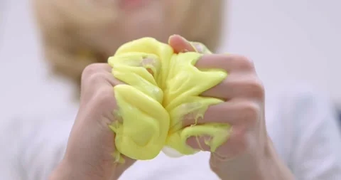 Little girl stretches yellow slime to th... | Stock Video | Pond5