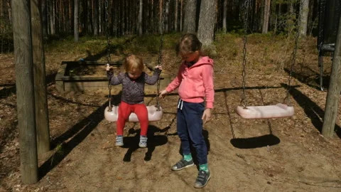 Little girl on swing set, older sister p... | Stock Video | Pond5