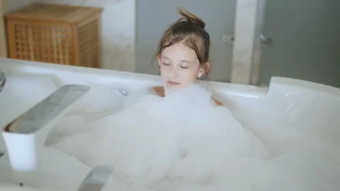 Little girl takes a bath full of foam. | Stock Video | Pond5