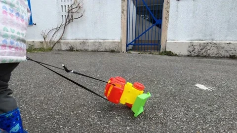 Little girl with a toy car on a string r... | Stock Video | Pond5