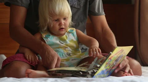 little girl turns over pages of book on ... | Stock Video | Pond5
