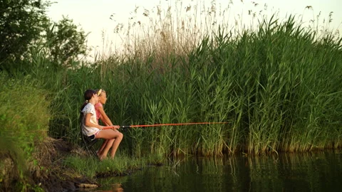 Little girls sitting with fishing rod on... | Stock Video | Pond5