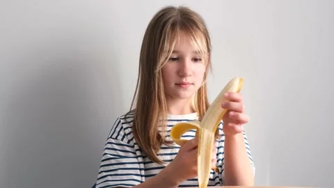 A little hungry girl eats a ripe yellow ... | Stock Video | Pond5