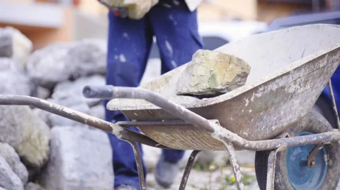 Loading wheelbarrow with big rocks close... | Stock Video | Pond5