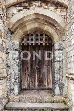 Photograph: Locked wooden door in old fortification wall #135930572