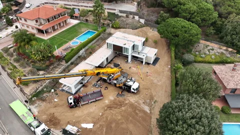 Long crane arrow lifting up modular home... | Stock Video | Pond5