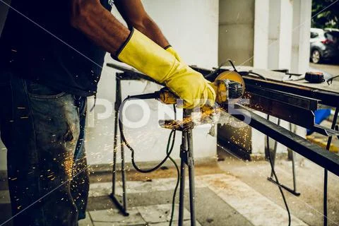 Photograph: Male construction worker using a tool to cut and polish ...