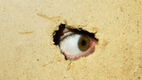 Male eye looking through hole in wall | Stock Video | Pond5