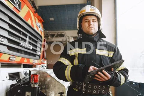 Male firefighter with tablet in uniform on car background ~ Hi Res ...