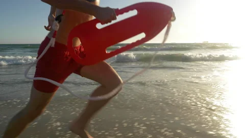 Male lifeguard running along the beach | Stock Video | Pond5