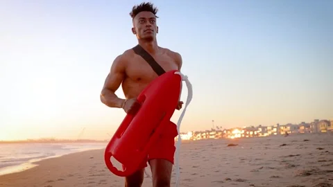 Male lifeguard running along the beach | Stock Video | Pond5