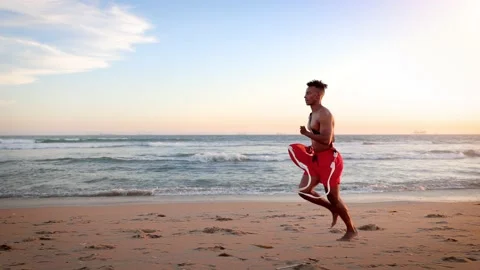 Male lifeguard running along the beach | Stock Video | Pond5