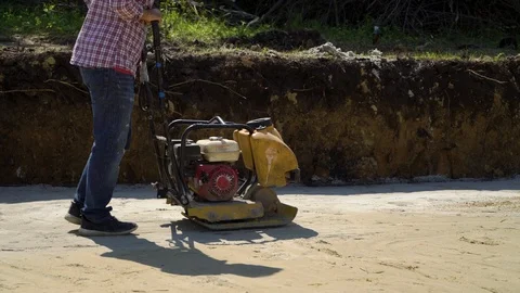 male worker ramming sand with plate comp... | Stock Video | Pond5