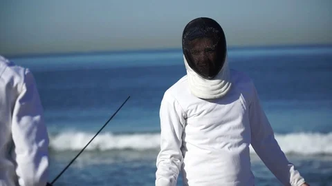 A man and woman fencing on the beach. | Stock Video | Pond5