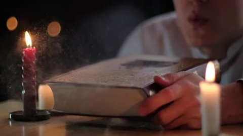 Man blows dust off an old book in the da... | Stock Video | Pond5