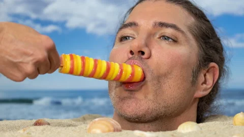 A man buried in sand on beach licking a ... | Stock Video | Pond5