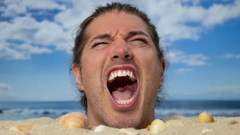 A man buried in sand on beach screaming | Stock Video | Pond5