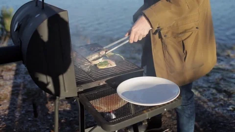 man cooking fish on the grill on the roc... | Stock Video | Pond5