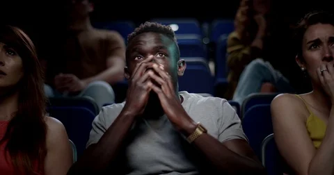 Man covers his face watching a scary mov... | Stock Video | Pond5
