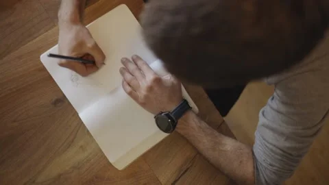Man drawing in a notebook on a desk | Stock Video | Pond5
