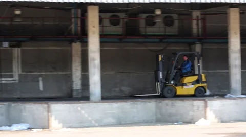 Man on a fork truck rides by ramp to aut... | Stock Video | Pond5