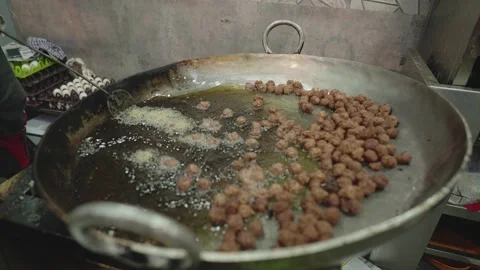 A man frying fritters in boiling oil in ... | Stock Video | Pond5