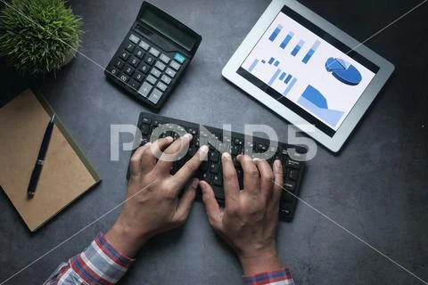 Photograph: Man hand typing on keyboard on office desk, analyzing chart ...