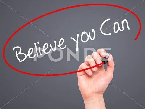 Man Hand writing Believe you Can with black marker on visual screen ...