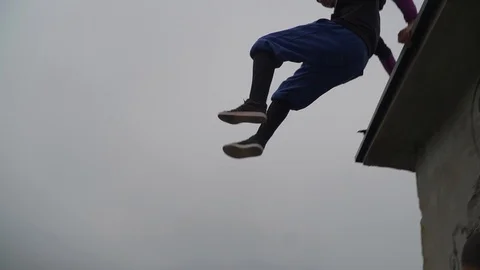 A Man Jumping Down From The Roof Before ... | Stock Video | Pond5