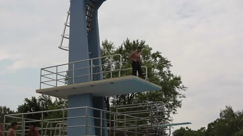 Man jumps off high diving board into swi... | Stock Video | Pond5