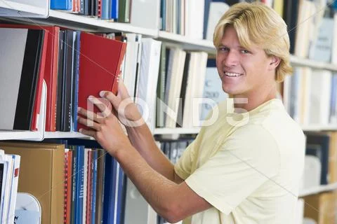 Man in library pulling book off a shelf (depth of field) ~ Premium ...