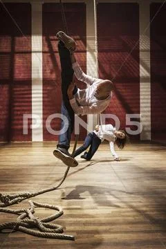 Man in mid-air pulling woman tied to rope against wall ~ Hi Res #58944543