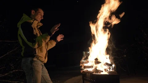 Man near brazier with fire and heats his... | Stock Video | Pond5