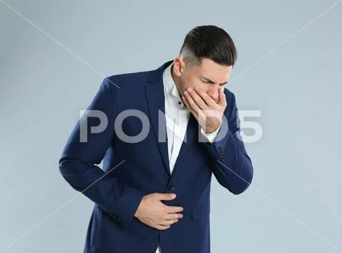 Man in office suit suffering from stomach ache and nausea on grey ...