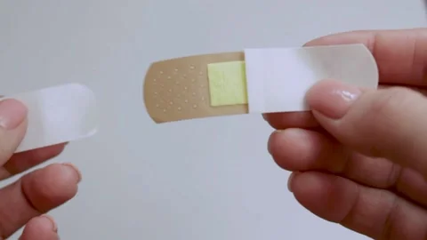 A man opens a Adhesive plaster. First ai... | Stock Video | Pond5