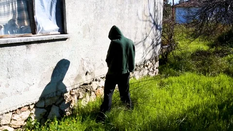 A man is peeing on the wall of a house | Stock Video | Pond5