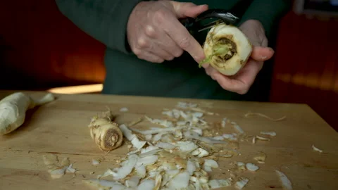 Man peeling the skin off of a parsnip ro... | Stock Video | Pond5