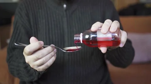 Man pouring cough syrup into a spoon to ... | Stock Video | Pond5
