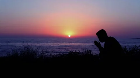 man praying by the sea at sunset | Stock Video | Pond5