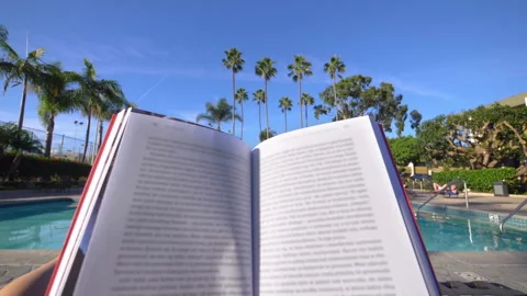 Man reading a book on a sunbed by the po... | Stock Video | Pond5