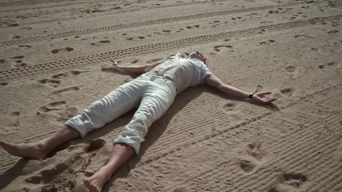 Man relaxing on sand. Man making angel o... | Stock Video | Pond5