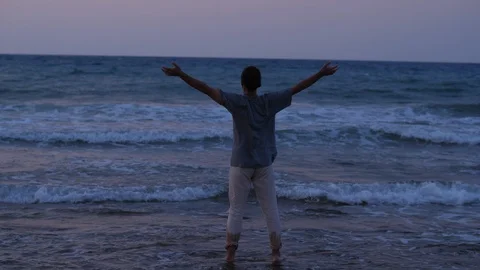 Man rise hands standing on sea beach at ... | Stock Video | Pond5