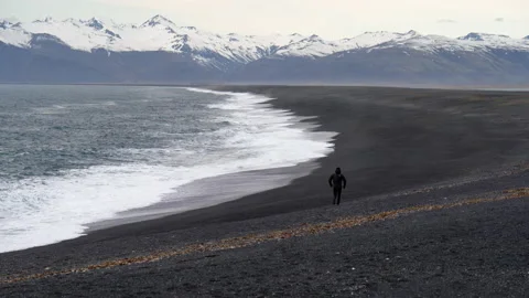 Man running along black sand beach by se... | Stock Video | Pond5