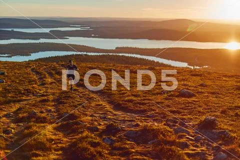 Man running on cliff top at sunset, Keimiotunturi, Lapland, Finland ...
