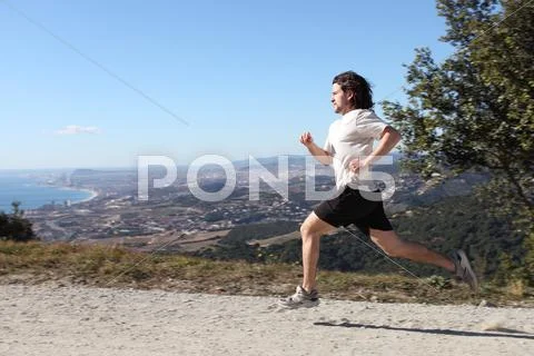 Man running on a path with a big city in the background ~ Hi Res #46644948